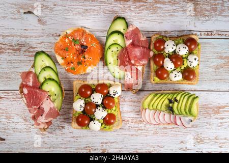 An assortment of sandwiches with fish, cheese, meat and vegetables lay ...