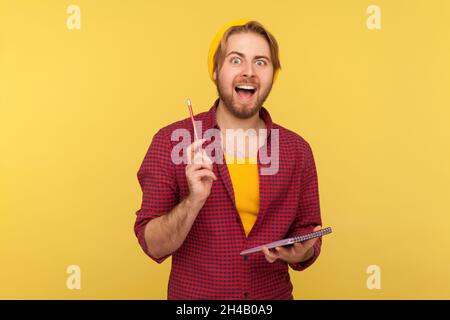 Excited guy writing in planner and smiling, writing down ideas in ...