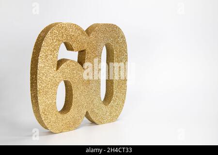 A gold glittery sign that says the number 60 on a white background ...
