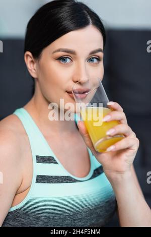 A woman in an orange sports bra and shorts stretches her arm while ...