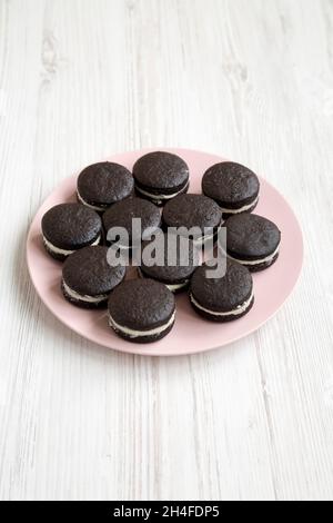 Homemade Oreos on a pink plate on a white wooden background, low angle ...
