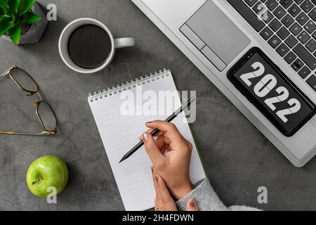 Overhead photo of woman holding pencil over notepad surrounded with ...