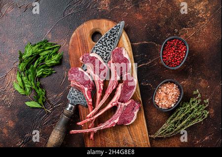 Raw lamb, mutton chops steaks on a wooden board. Dark background. Top ...