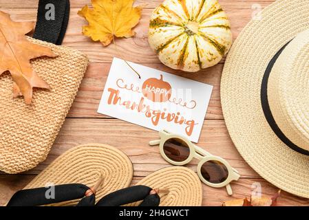 Stylish bag, sunglasses, pumpkin, flip flops, dry leaves and paper card ...