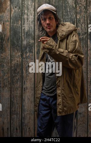 Junkie man with cap green anorak and blue sweatpants near wooden old ...