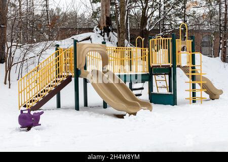 Playground in park without kids, covered with snow in winter season ...