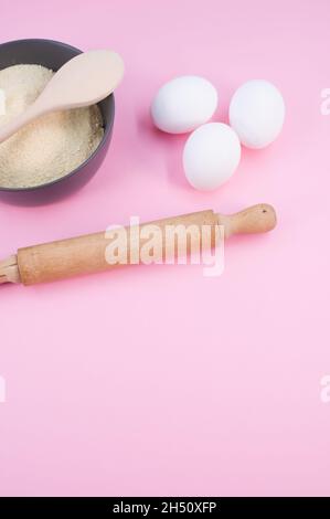dark stoneware bowl with flour wooden rolling pin and white eggs on a blue background Stock ...