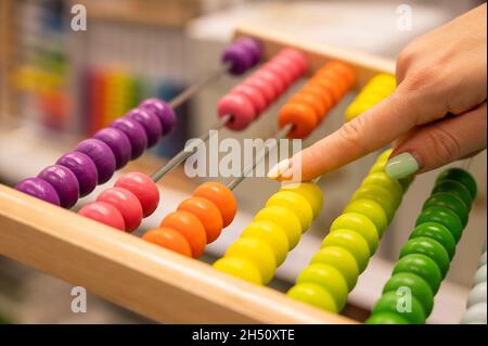 Closeup female hand calculating with balls on wooden rainbow abacus for ...