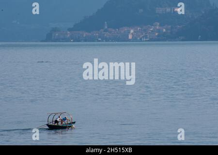 Traditional standing rowboat “Lucia” crossing lake como, Italy. Men ...
