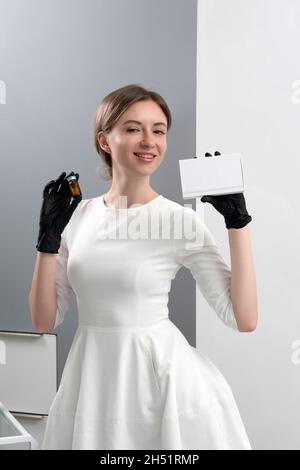 Woman cosmetologist demonstrates product. Smiling girl holding henna ...