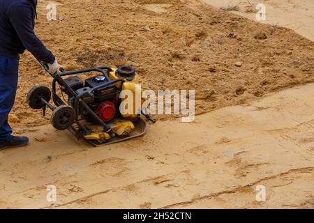 Worker in use vibratory plate compactor for compaction sand during path ...