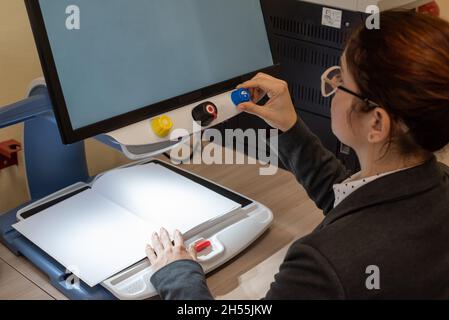 A visually impaired woman uses special reading equipment Stock Photo ...