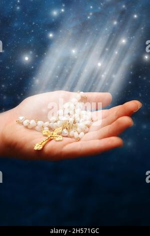 Hand keeping Christian cross rosemary over blue backround with rays of ...