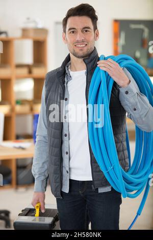 Hand holding white plastic pipes against a background of more pipes ...
