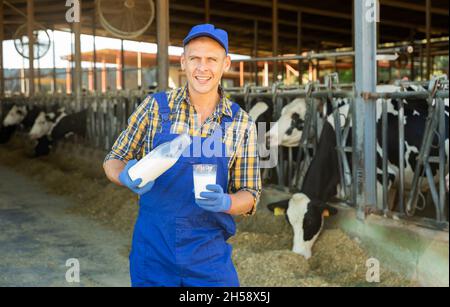 Farmer in cowhouse with bottle of milk Stock Photo - Alamy