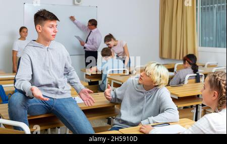 Positive students are talking about homework at the desk Stock Photo ...