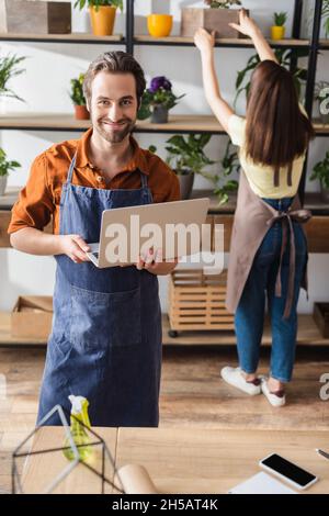 Positive florists holding plants and looking at each other in flower ...