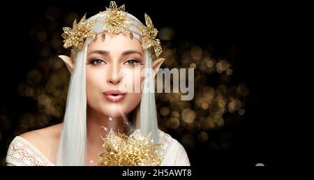 Attractive elf queen with golden flowers looking at camera while ...