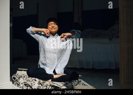 Asian women relaxing stretching arms sitting on sofa in bright living ...
