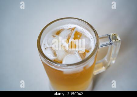 Glass mug with fresh cold beer on wooden bench in winter outdoor cafe ...