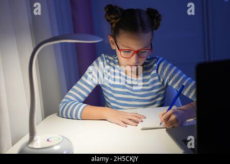 girl doing homework near computer and nanny sitting with book on ...