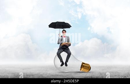 young businessman with an umbrella and a book Stock Photo - Alamy