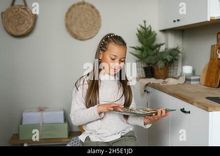 Beautiful girl holds a plate of Christmas cookies in her hands in the ...