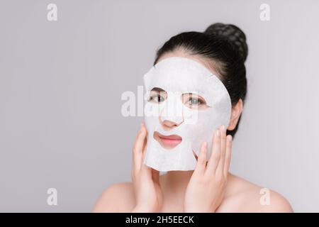 Beautiful asian woman applying paper sheet mask on her face white ...