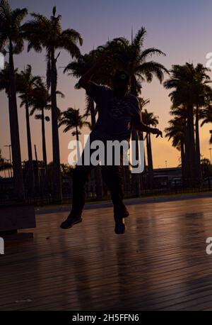 Young person breakdancing in a park surrounded by palm trees in the ...