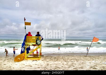 Two Lifeguards sit in high wooden beach chair watching swimmers on the ...