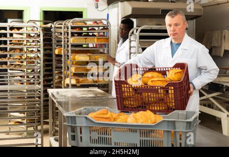 Portrait of successful baker during daily work behind counter in small ...