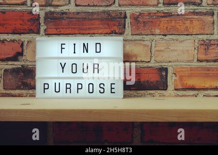 Find your purpose word in light box on brick wall and wooden shelves ...