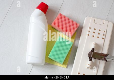 A beige mop, sponges and a bottle of floor cleaner. Cleaning products ...