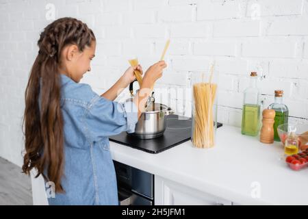 Preteen kid holding salt mill near saucepan in kitchen Stock Photo - Alamy