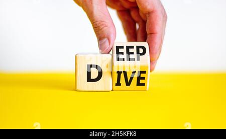 Deep dive symbol. Businessman turns a wooden cube with words 'Deep dive ...