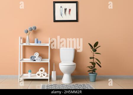 Interior of restroom with toilet bowl and shelving unit near blue wall ...