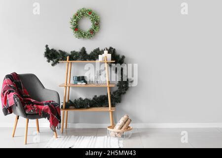 Shelving unit with Christmas branches, candles and books near white ...