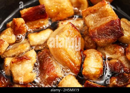 Tasty cracklings in frying pan isolated on white. Cooked pork lard ...