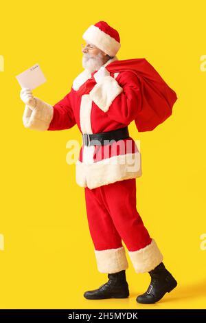 Going Santa Claus with letter and gifts on sledge against red ...