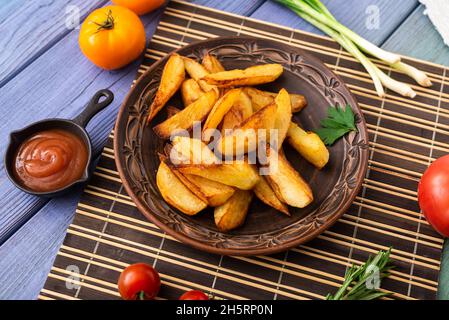 Fried potatoes in large pieces on a plate on the table with different ...