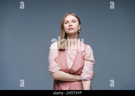 Modest and naive woman with blond hair, stylishly dressed in pink vest ...