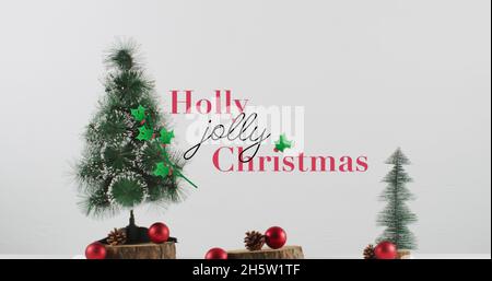 Image of holly text over snow falling and christmas decorations on ...
