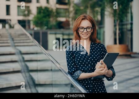 Beautiful redhead woman wearing glasses over isolated background with a ...