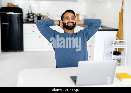 Successful hispanic male freelancer at the workplace, looks directly at ...