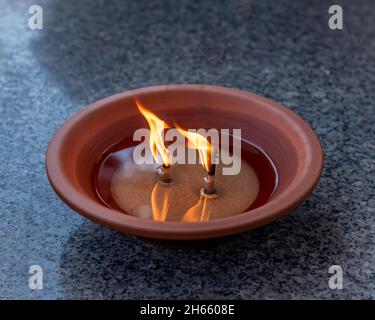 Grave light with burning candle on a grave with flowers Stock Photo - Alamy