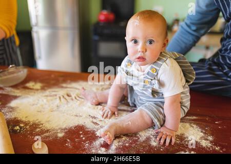 Little son sitting on kitchen counter and eating spoon of berry jam ...