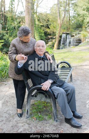 Two woman sat on bench with brown labrador type dog on lead sat ...