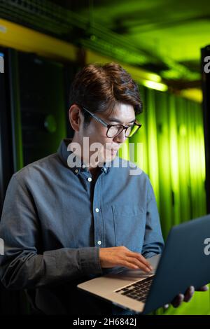 Asian male engineer using a laptop in computer server room Stock Photo ...