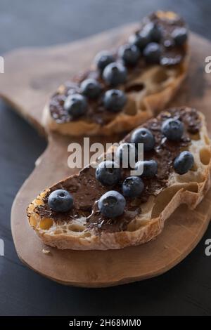 Wooden board of tasty toasts with hazelnut butter on pink background ...