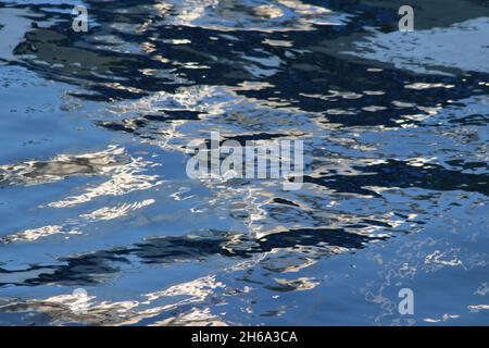 Shapes and colours in reflections of fishing boats in water of harbour ...